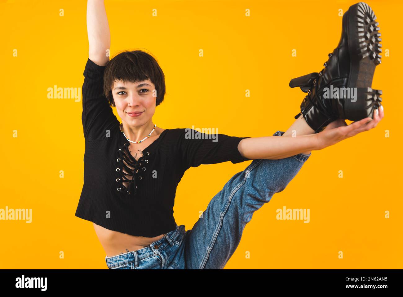 Flexible female dancer showing her skills by stretching one leg up and ...