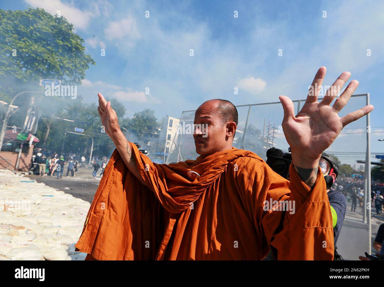 A Thai Buddhist monk raises his hands to policemen to stop firing tear ...