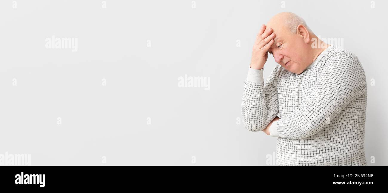 Elderly man suffering from mental disability on light background with ...