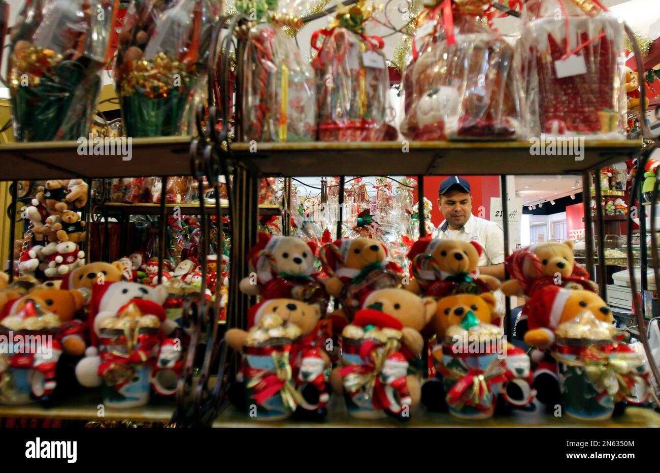 An employee works at a booth selling Christmas teddy bears at a ...