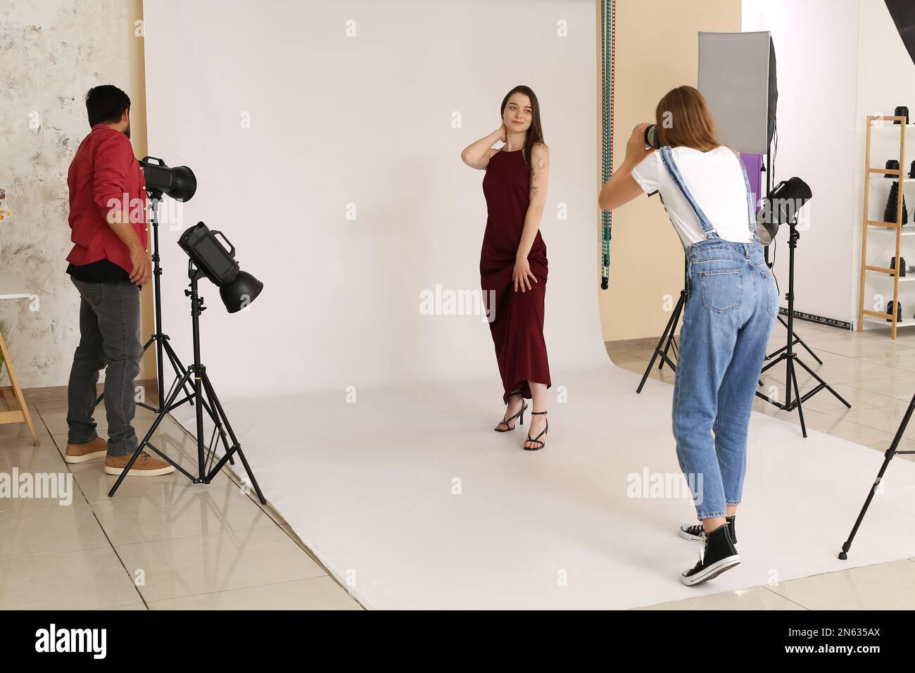 Female photographer and her assistant working with beautiful model in ...