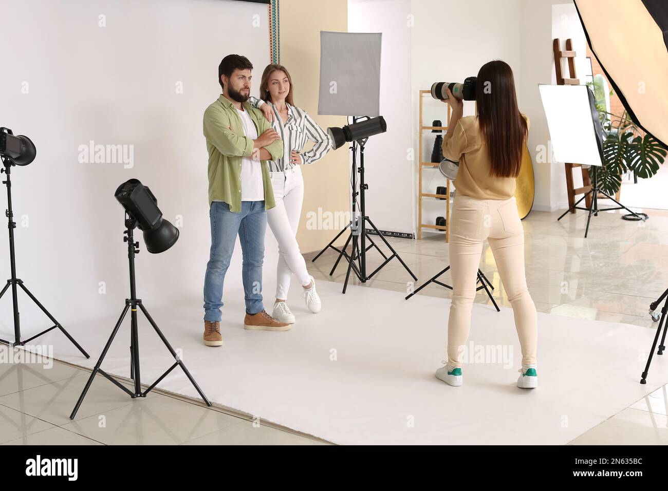 Female photographer taking picture of models in studio Stock Photo - Alamy