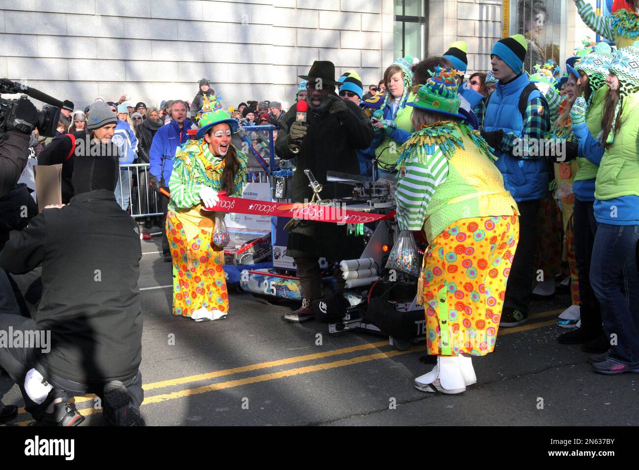 Parade host Al Roker, center in dark hat and coat holding microphone ...