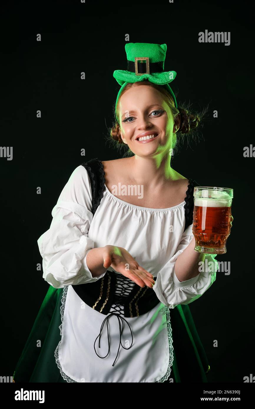 Irish waitress with glass of beer on dark background. St. Patrick's Day ...