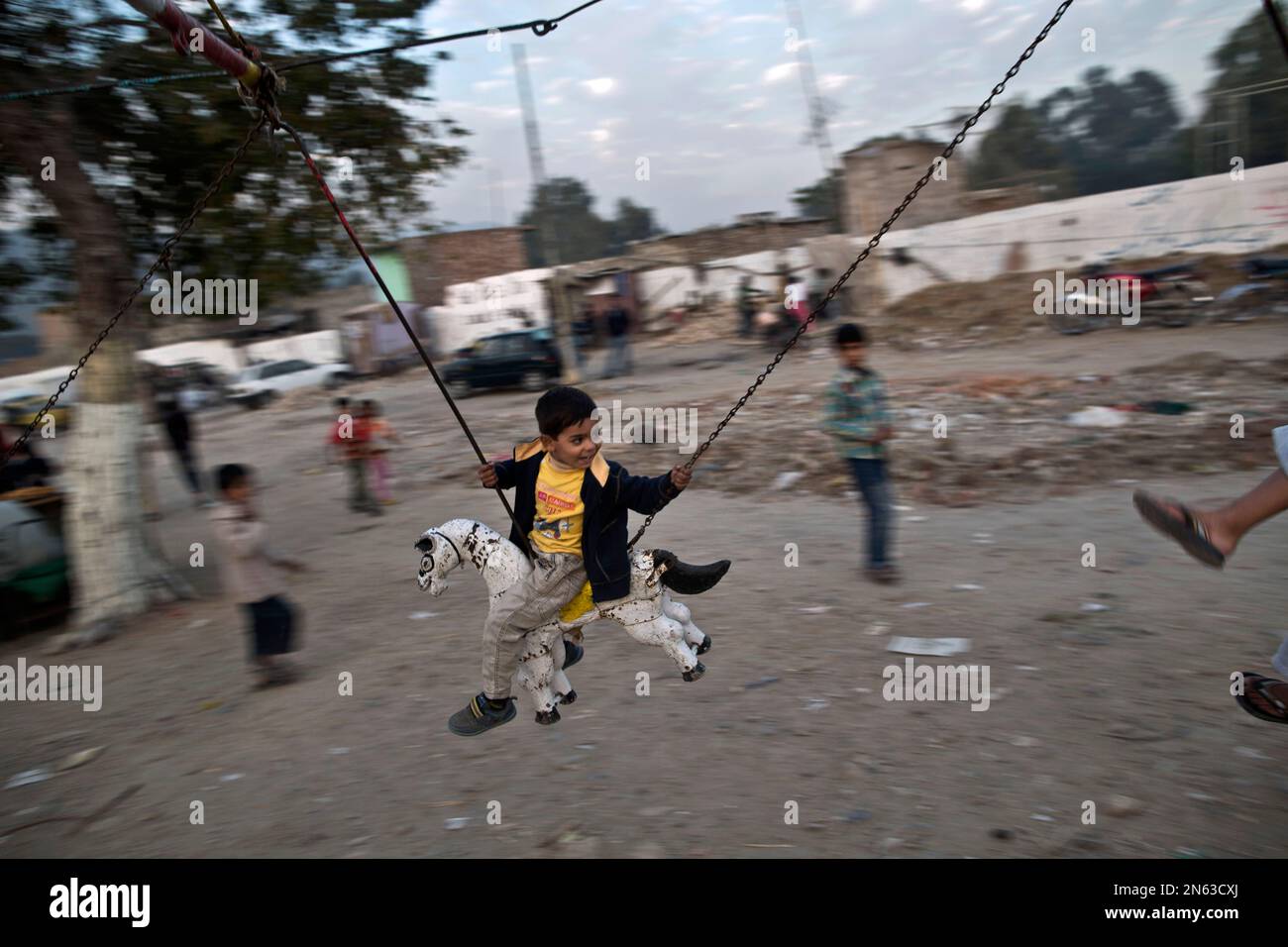 A Pakistani child enjoys a ride on a merry-go-round, costing 10 Rupees ...