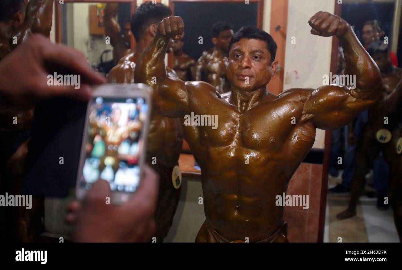 A man takes a picture on his cell phone of an Indian body builder ...