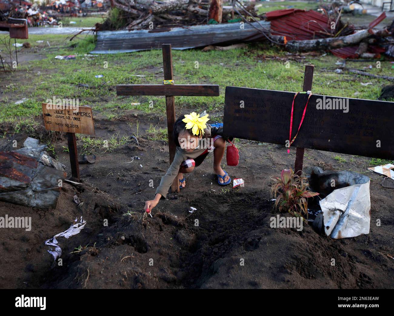 Typhoon survivor Jaysel Mosquito, 6, places a candy on the grave of her ...
