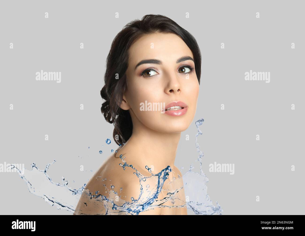 Beautiful young woman and splashing water on light grey background. Spa ...