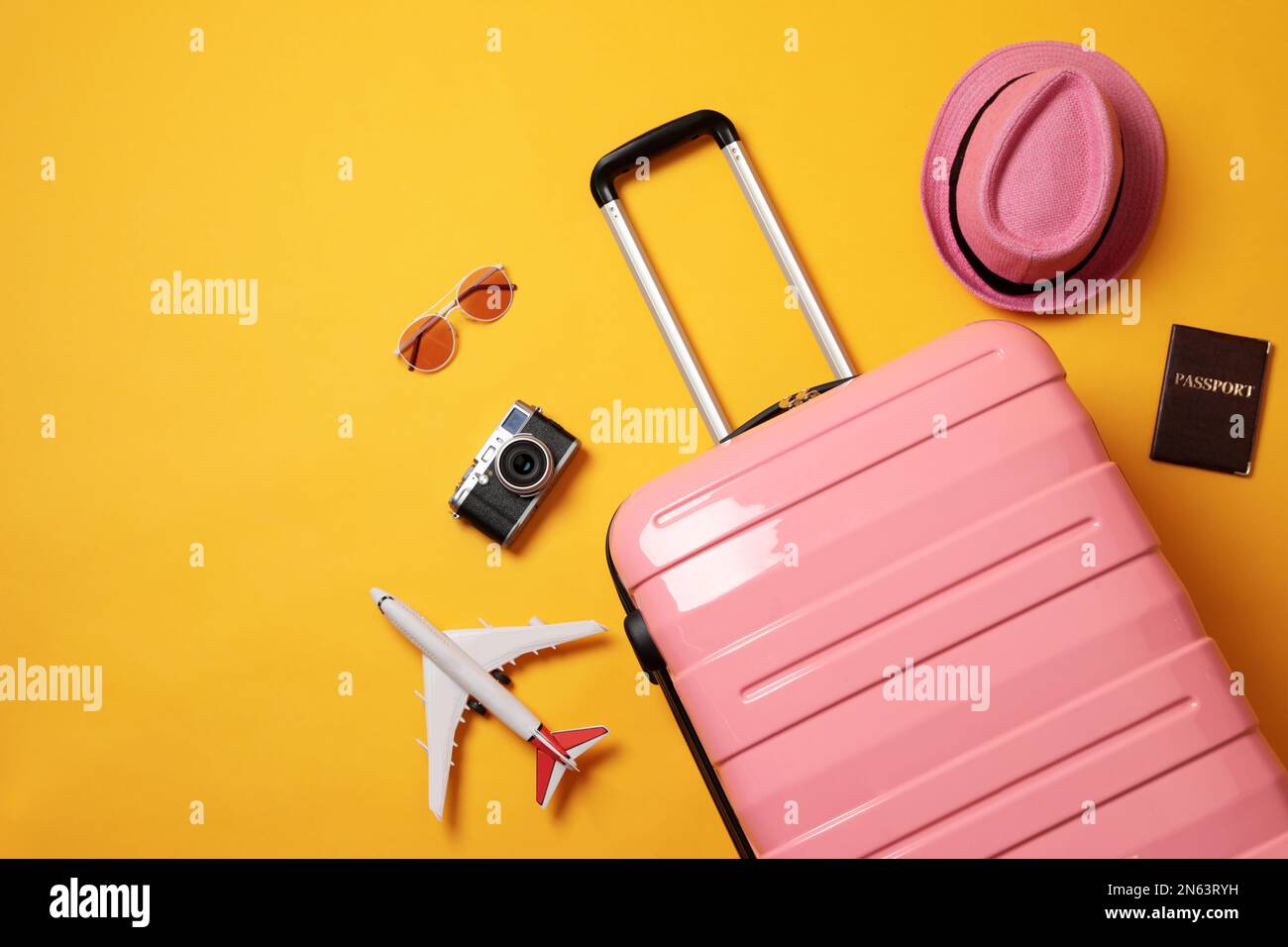 Flat lay composition with suitcase and travel accessories on yellow ...
