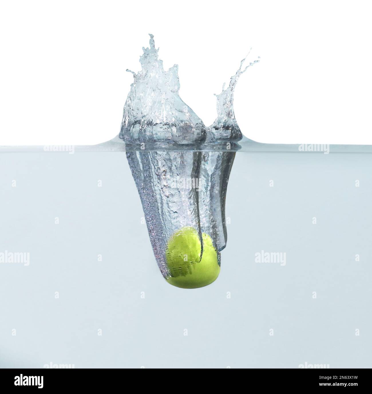 Ripe green apple falling down into clear water with splashes against ...