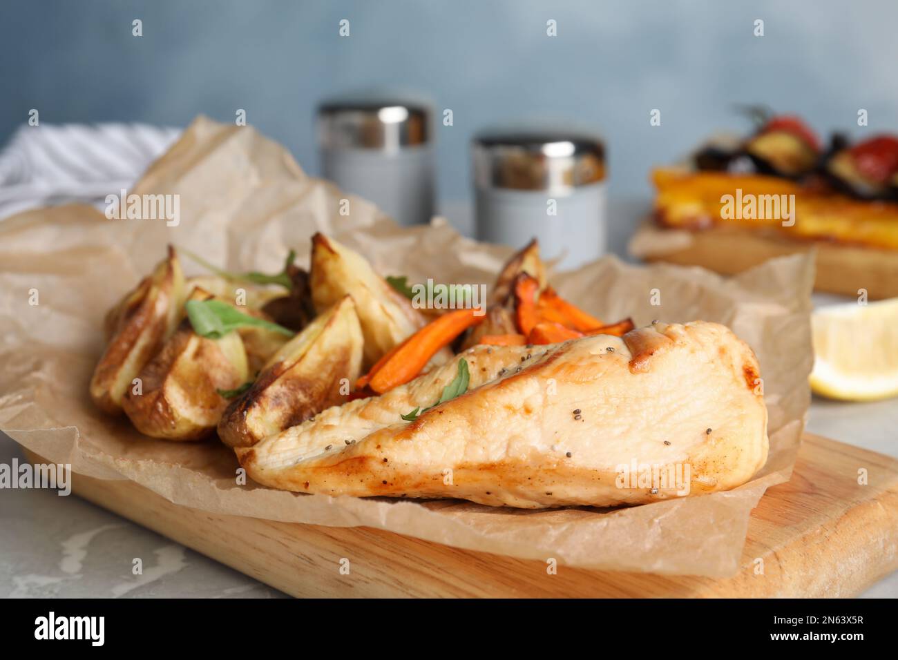 Delicious cooked chicken and vegetables on grey marble table, closeup ...