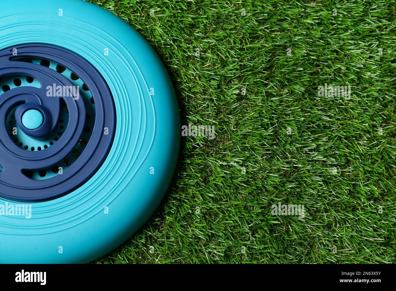 Light blue plastic frisbee disk on green grass, top view. Space for ...