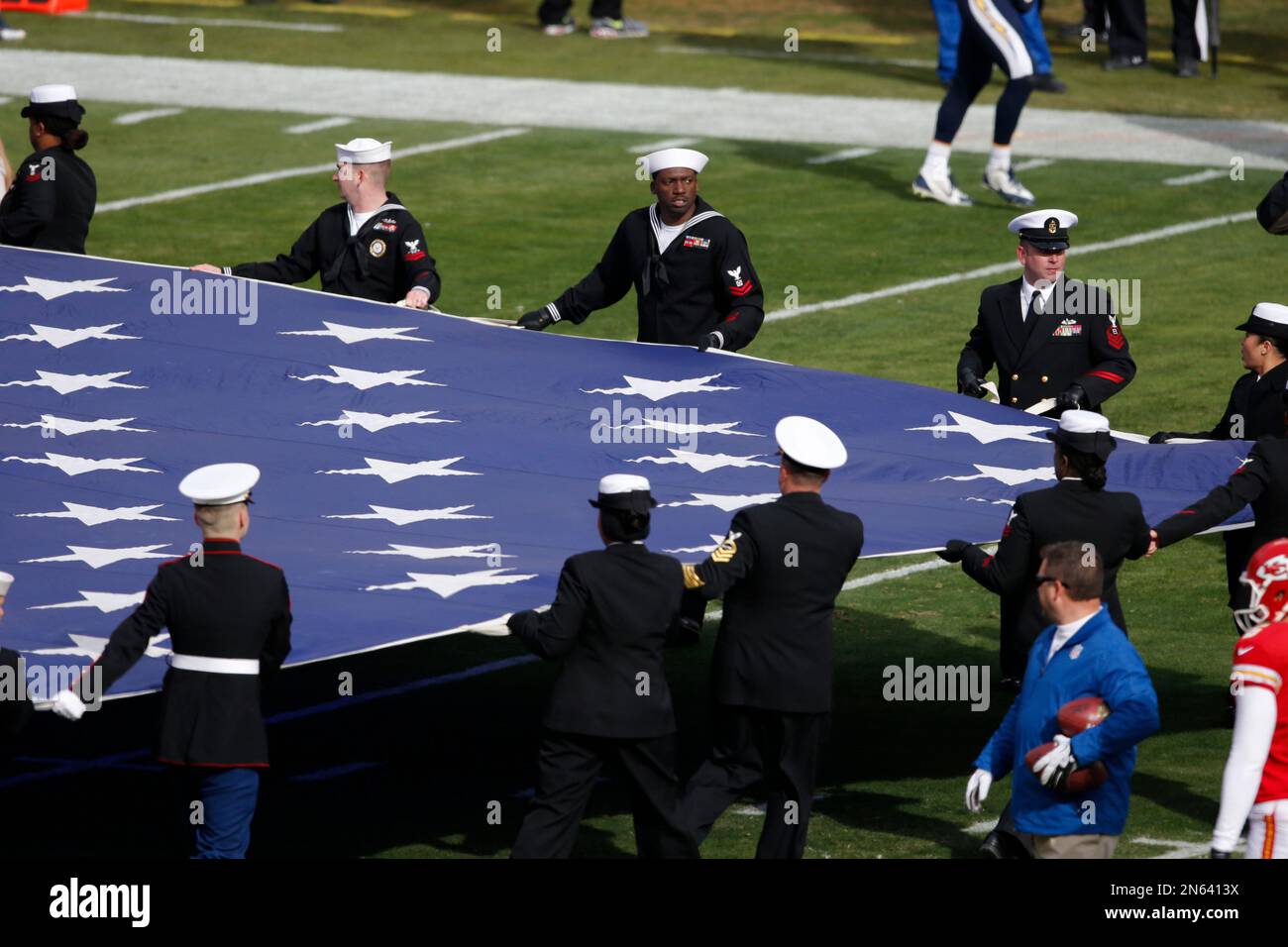 Members of the military unfold a giant flag before an NFL football game ...