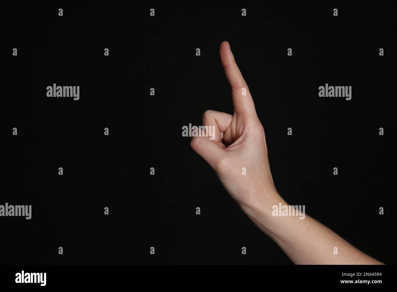 Woman pointing at something on black background, closeup. Finger ...