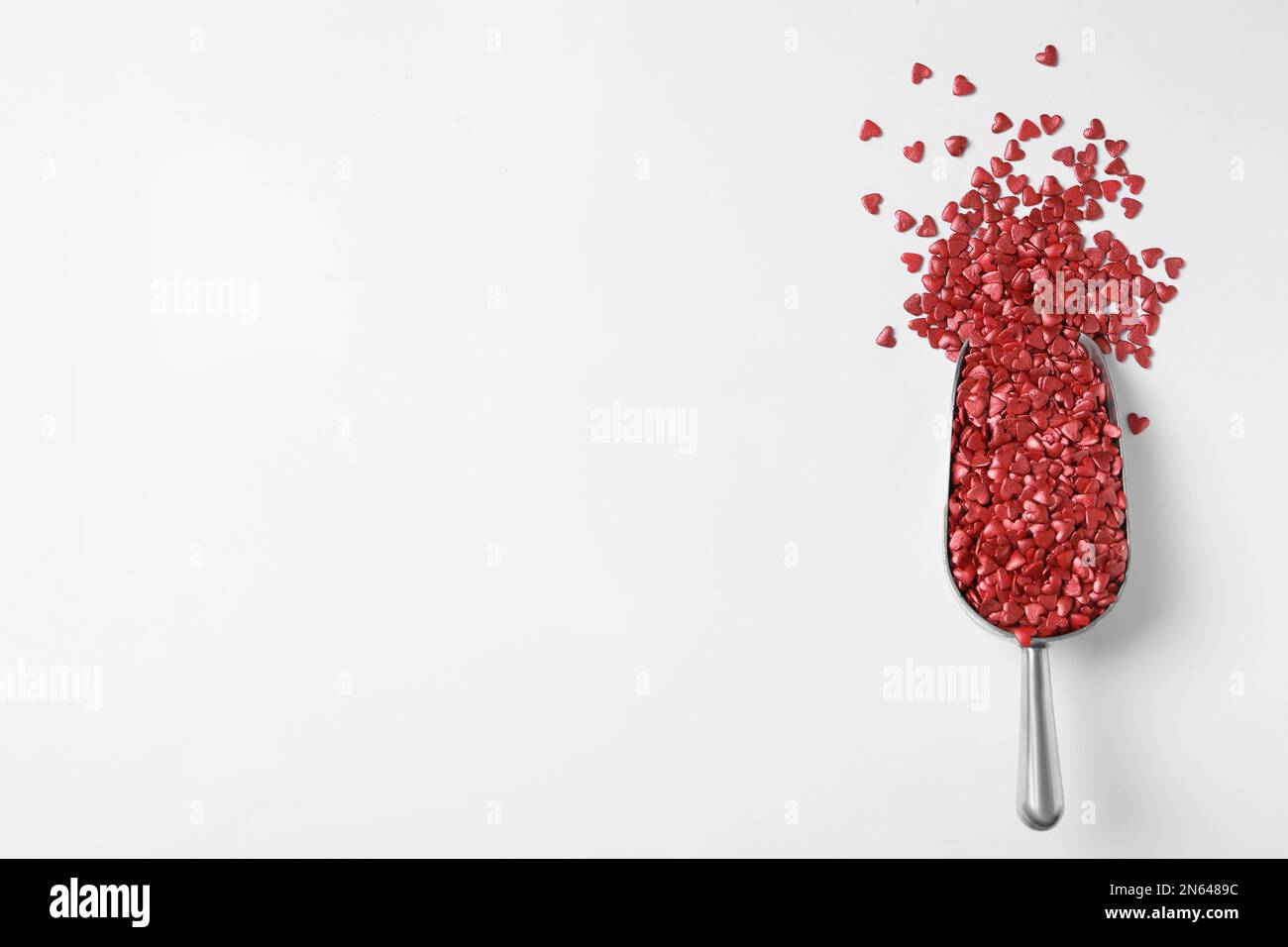 Bright heart shaped sprinkles in scoop on white background, top view ...