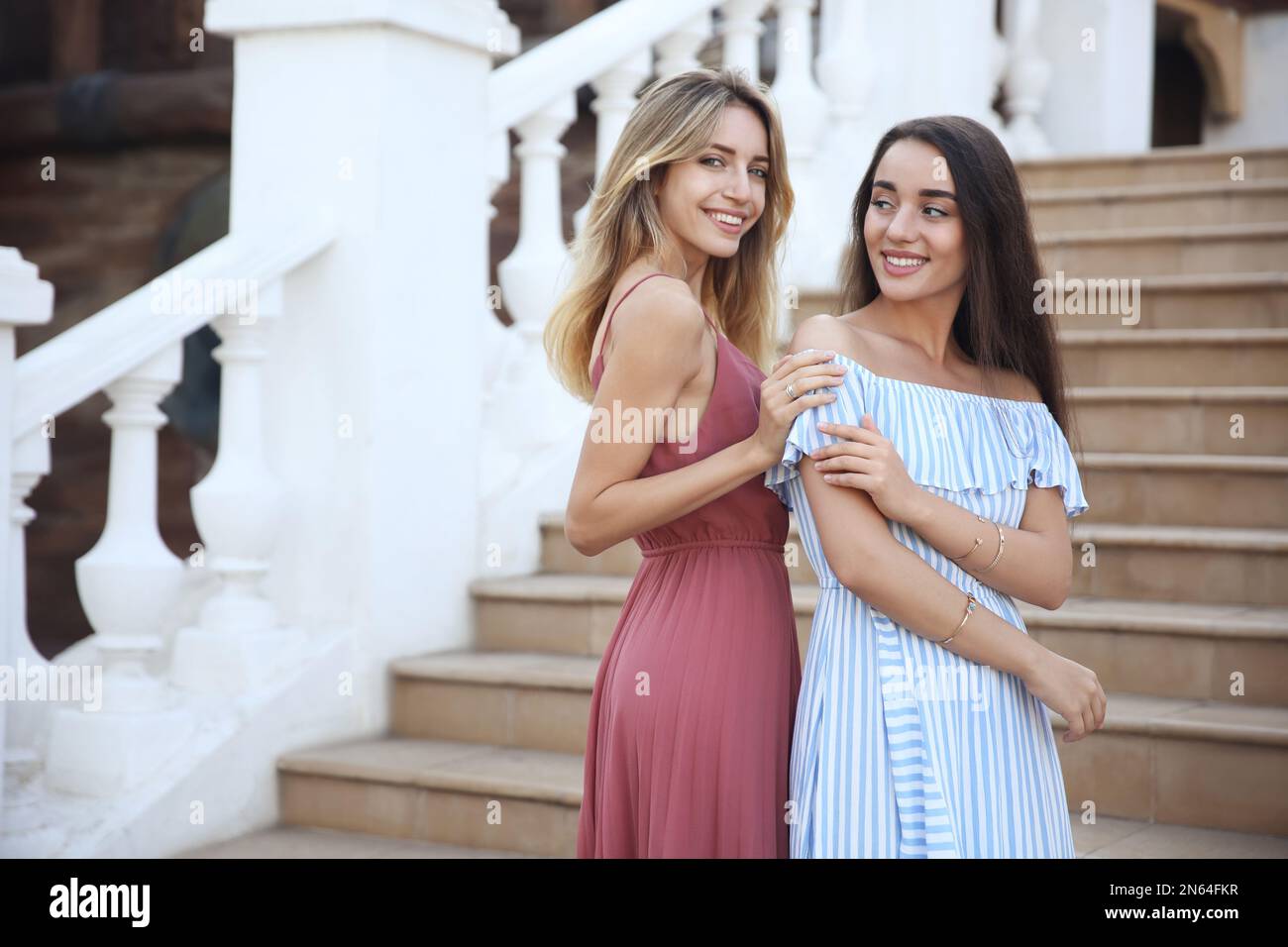 Beautiful young women in stylish dresses on stairs outdoors Stock Photo ...