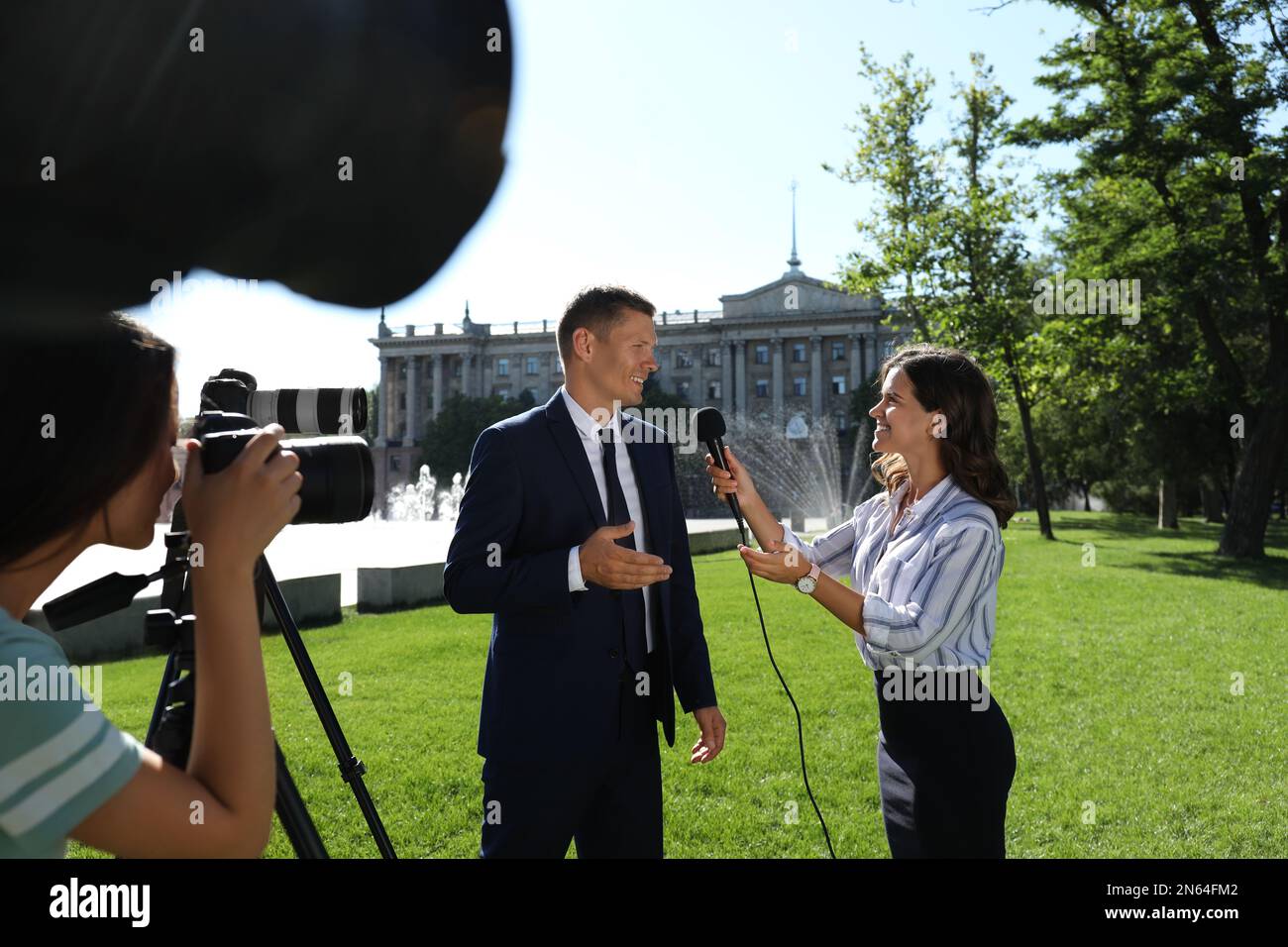 Professional journalist and operator with video camera taking interview ...