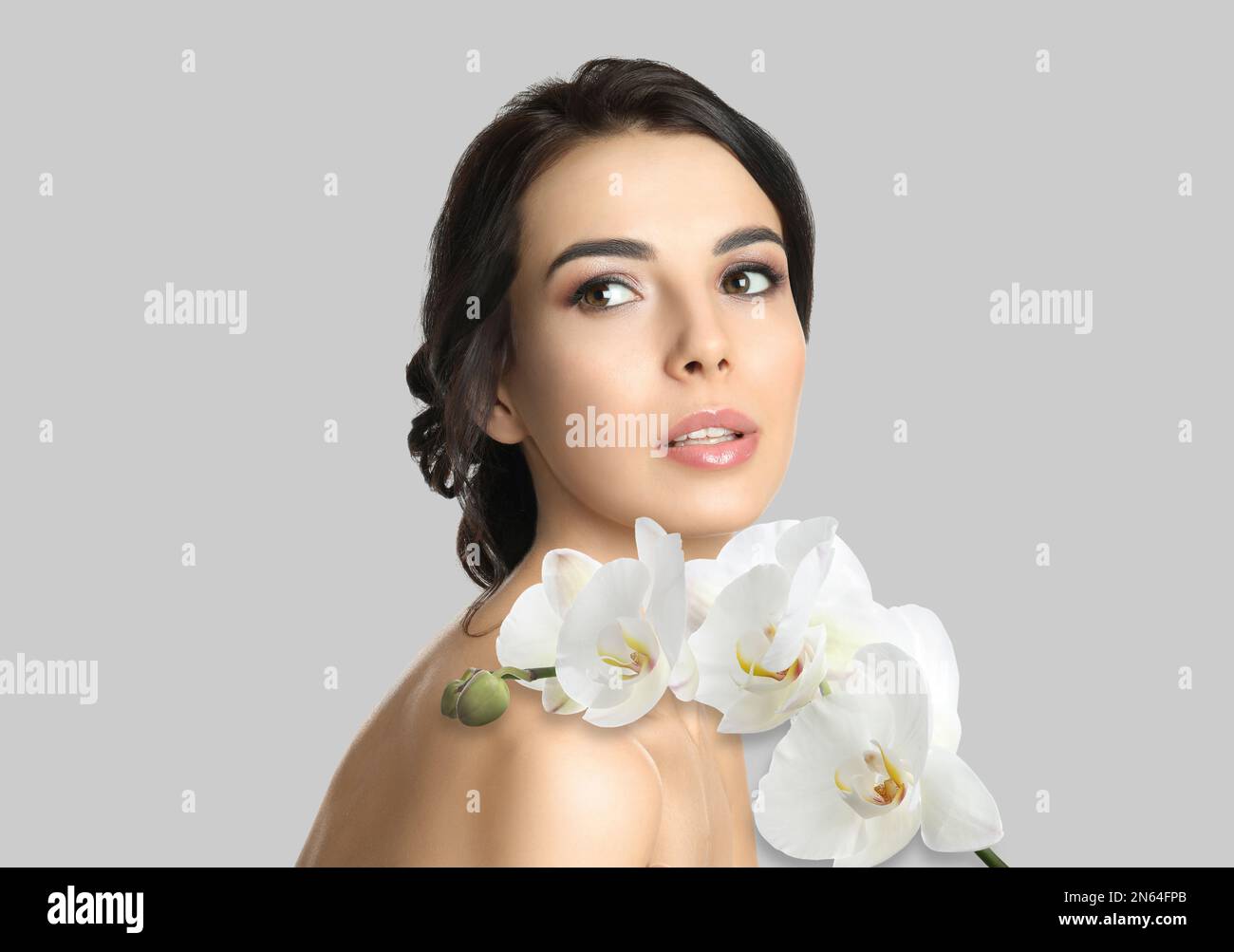 Beautiful young woman and orchid flowers on light background. Spa ...
