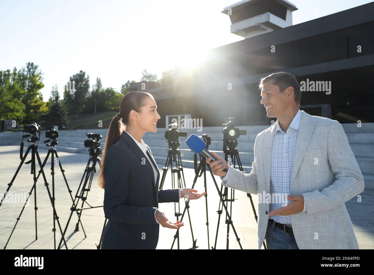 Professional journalist interviewing young woman on city street Stock ...