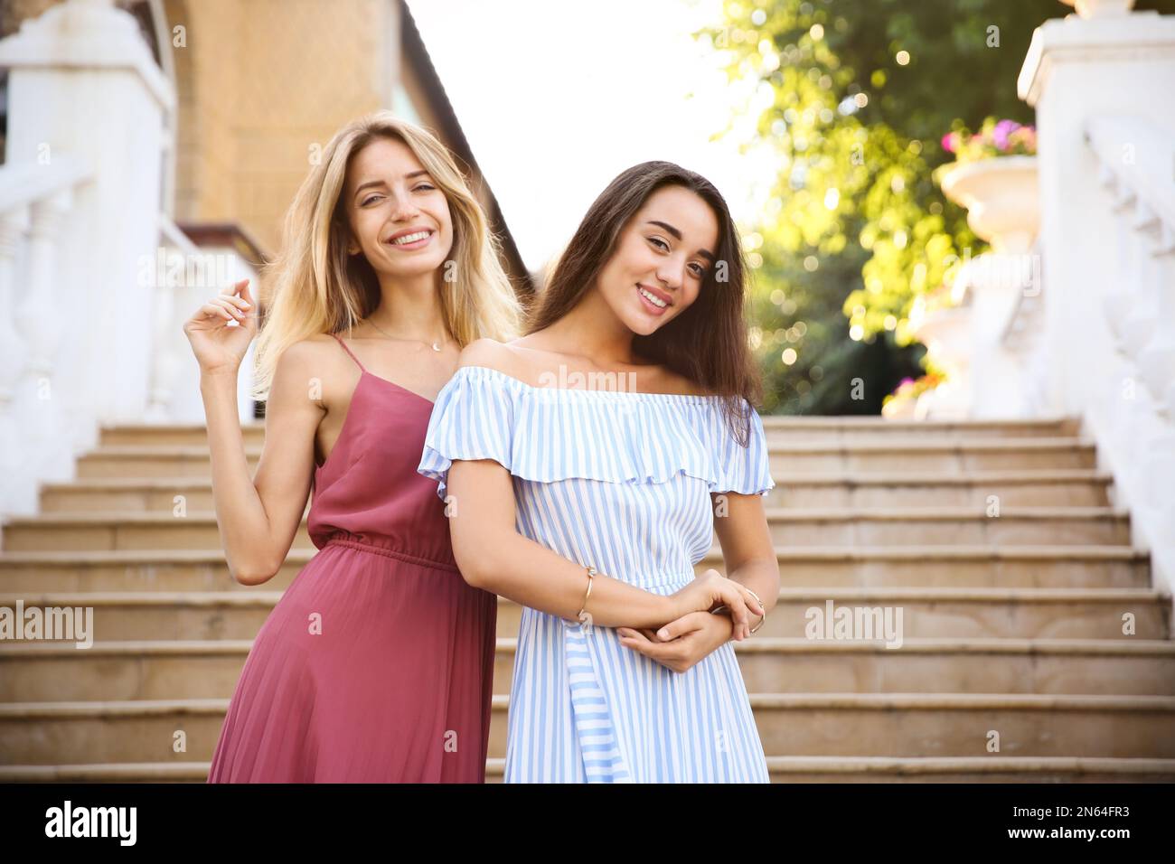 Beautiful young women in stylish dresses on stairs outdoors Stock Photo ...