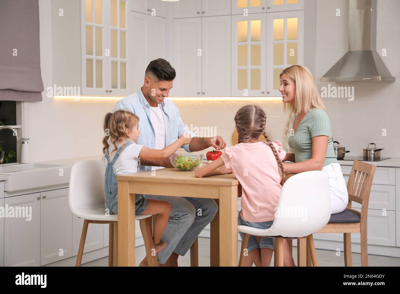 Happy family cooking together at table in modern kitchen Stock Photo ...