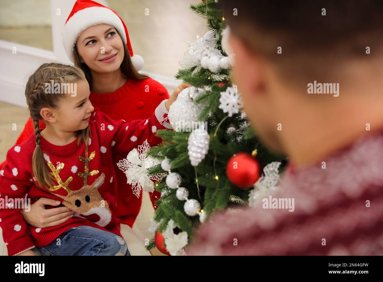 Happy family with cute child decorating Christmas tree together indoors ...