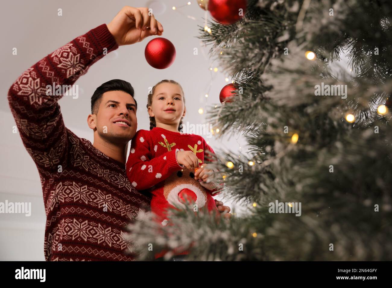 Happy father with his cute daughter decorating Christmas tree together ...