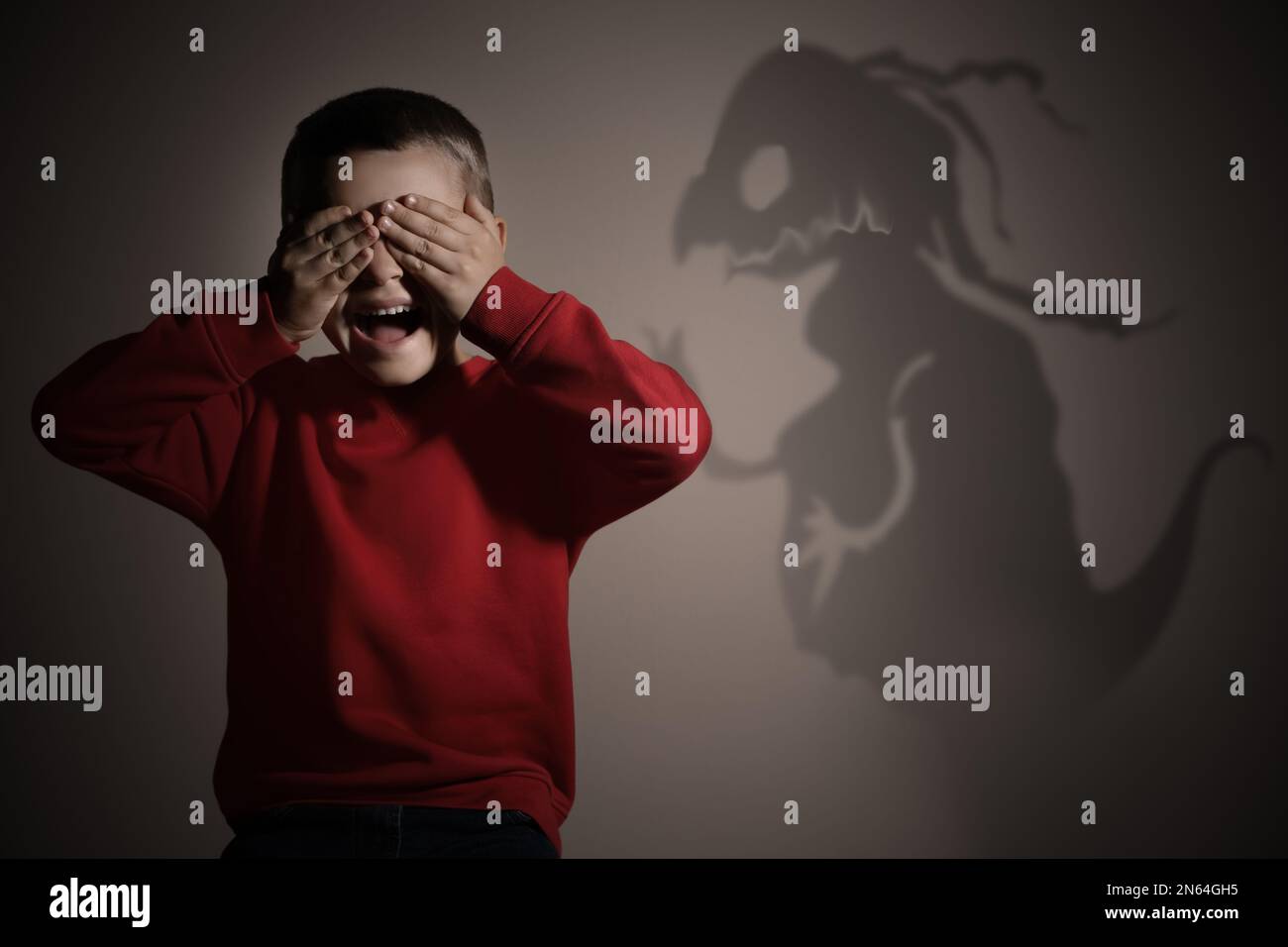 Shadow of monster and scared little boy on beige background Stock Photo ...