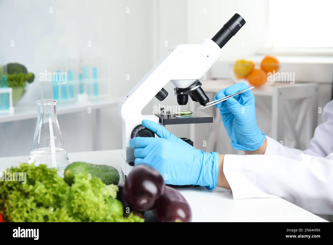 Scientist Inspecting Slice Of Cucumber With Microscope In Laboratory