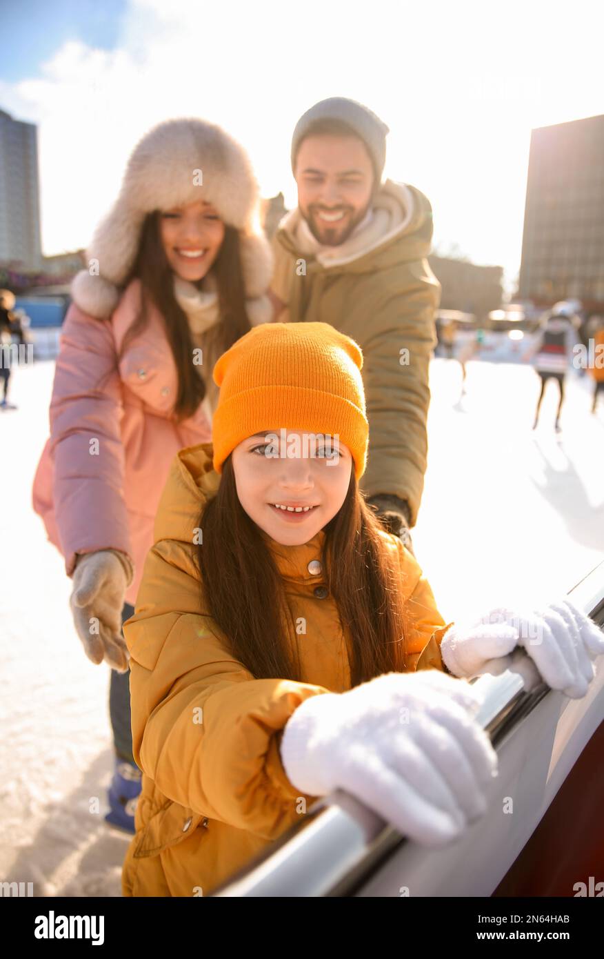 Cute little girl with her parents at outdoor ice skating rink Stock ...