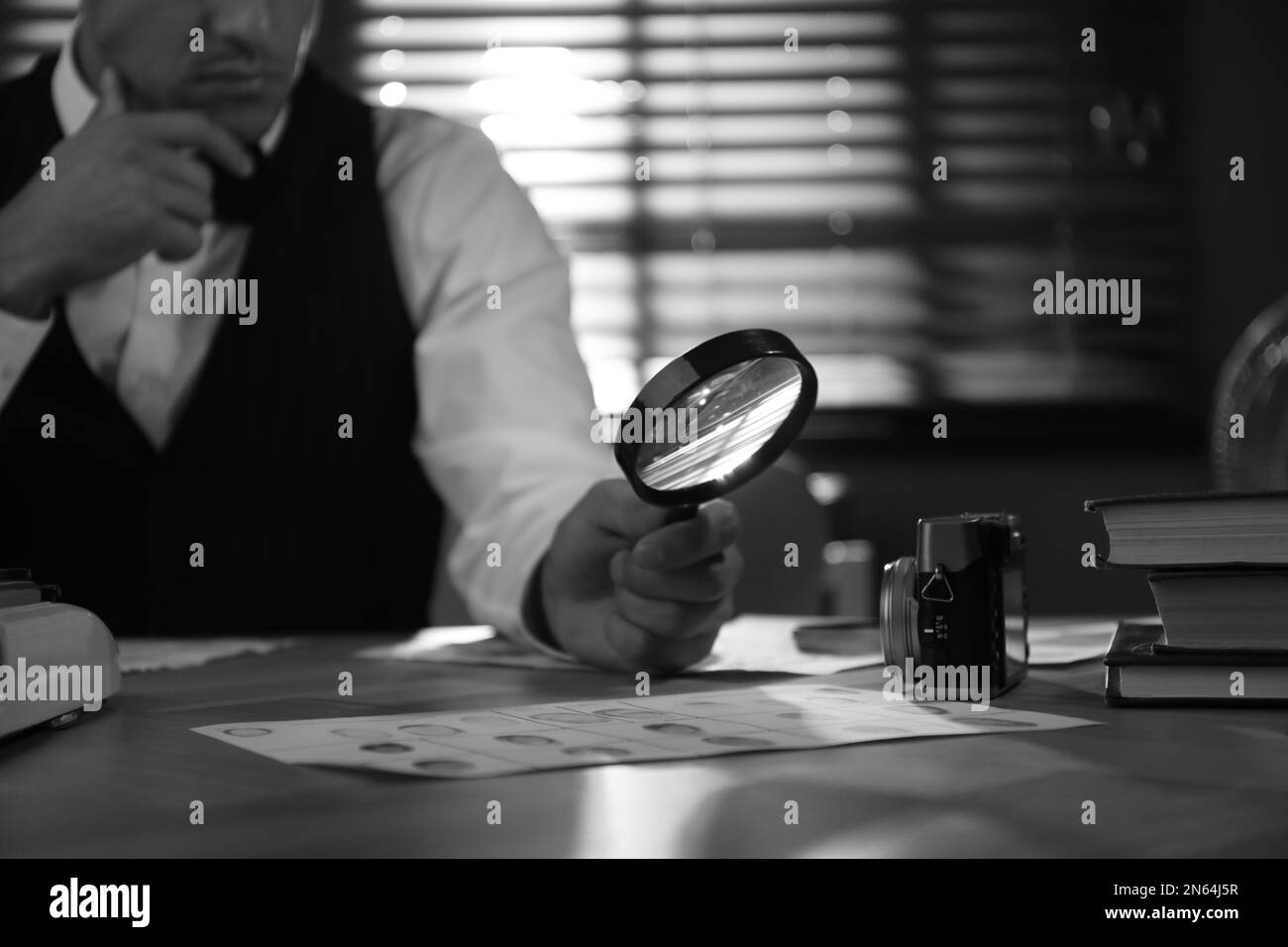 Old fashioned detective with magnifying glass working at table in ...