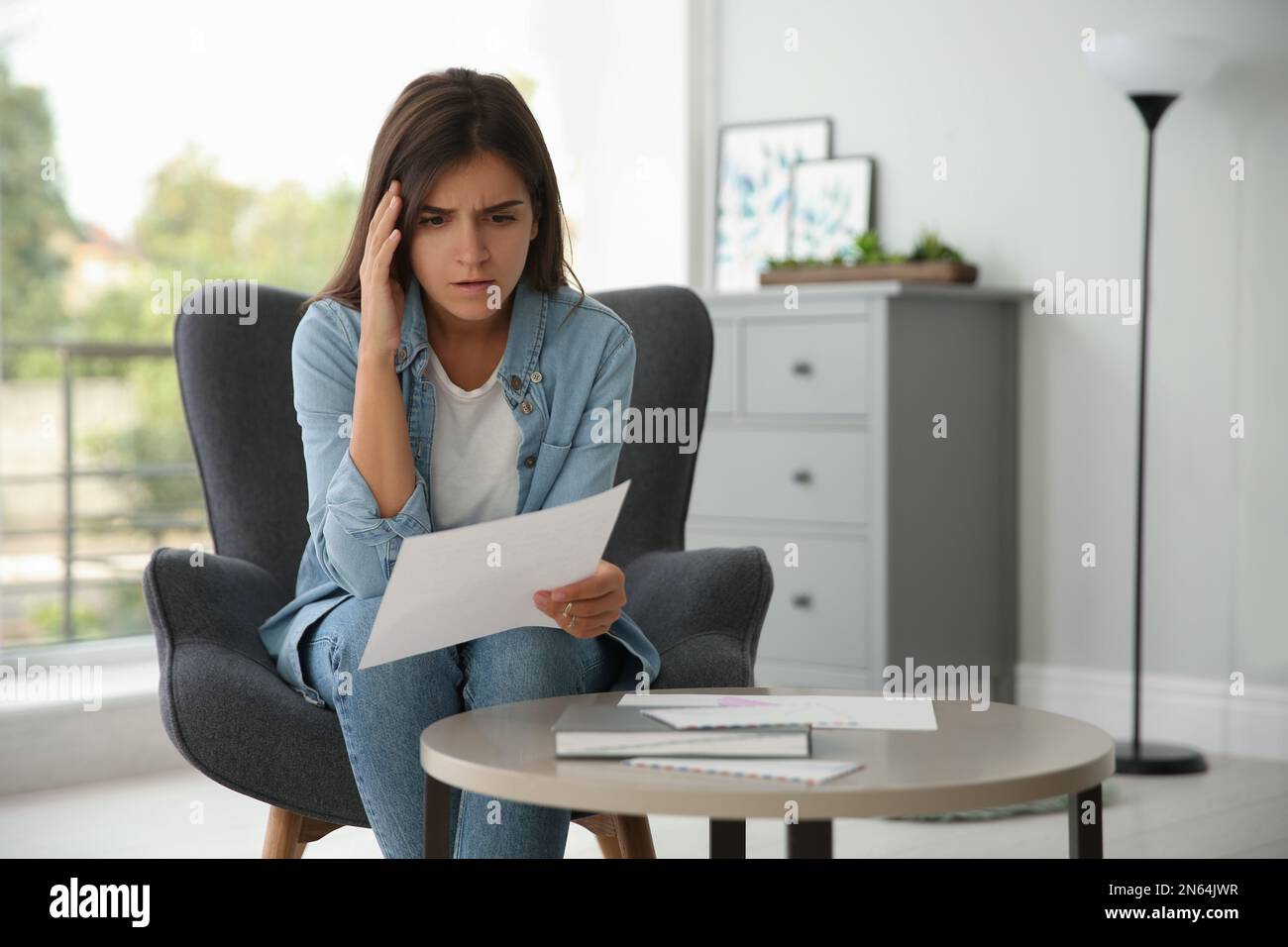 Worried woman reading paper letter at home Stock Photo - Alamy