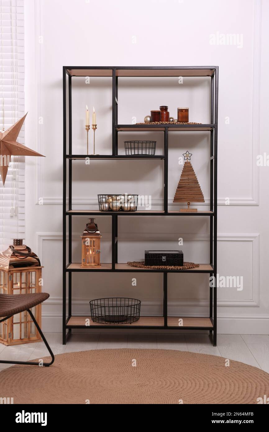 Stylish shelving unit with different decor near white wall indoors ...