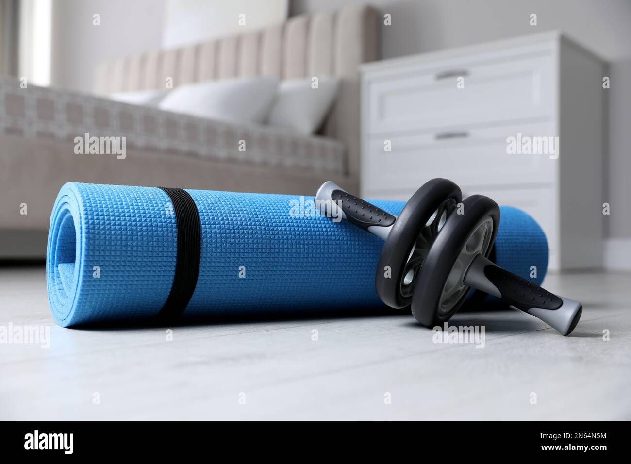 Abs roller and yoga mat on floor indoors. Fitness at home Stock Photo ...
