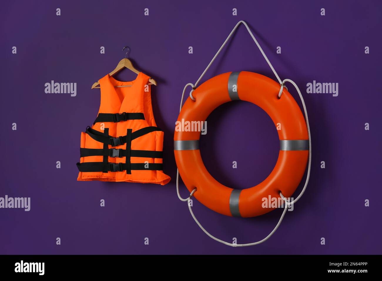 Orange life jacket and lifebuoy on violet background. Rescue equipment ...