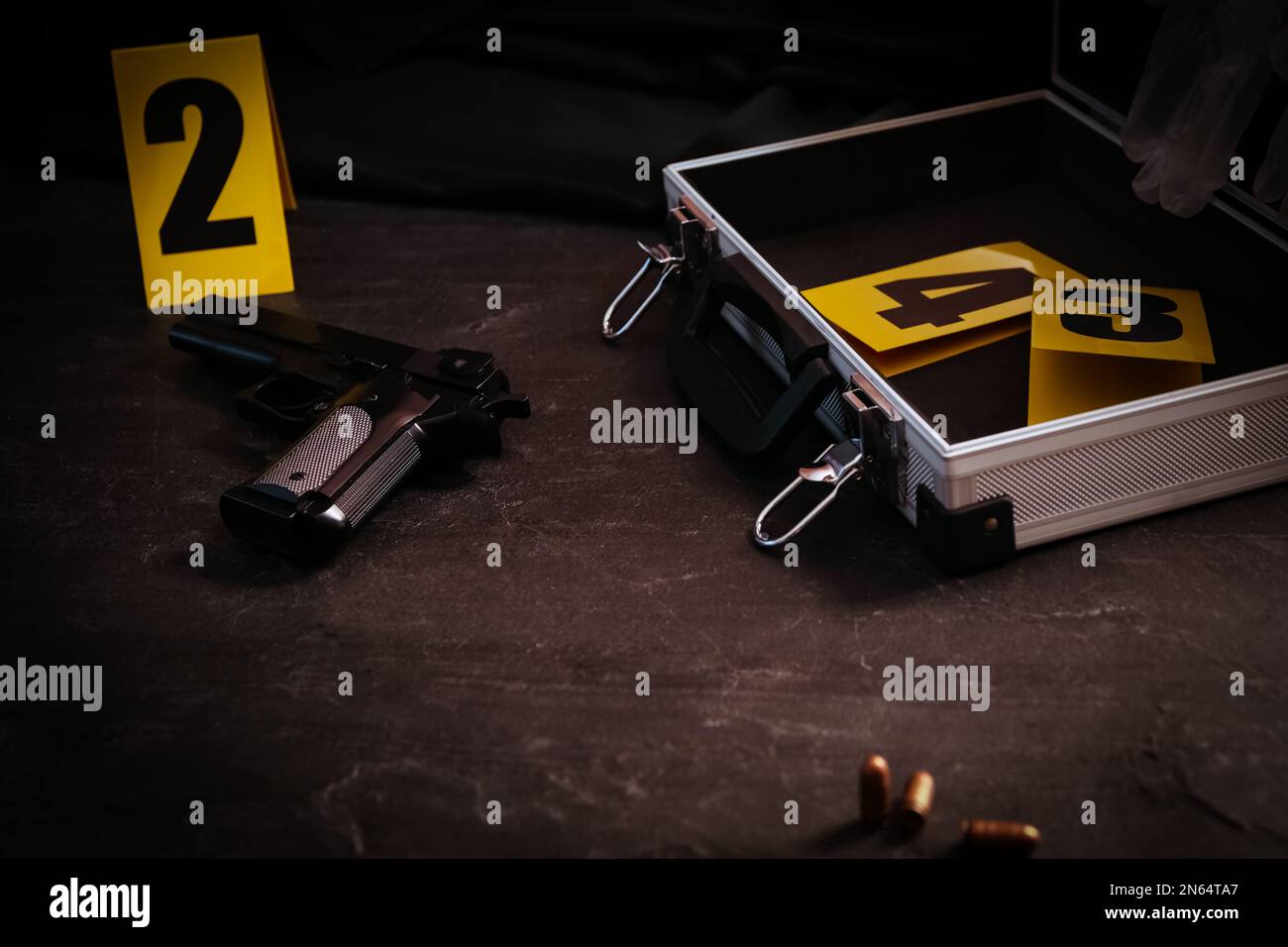 Gun and open case with evidence markers on black slate table. Crime scene Stock Photo - Alamy
