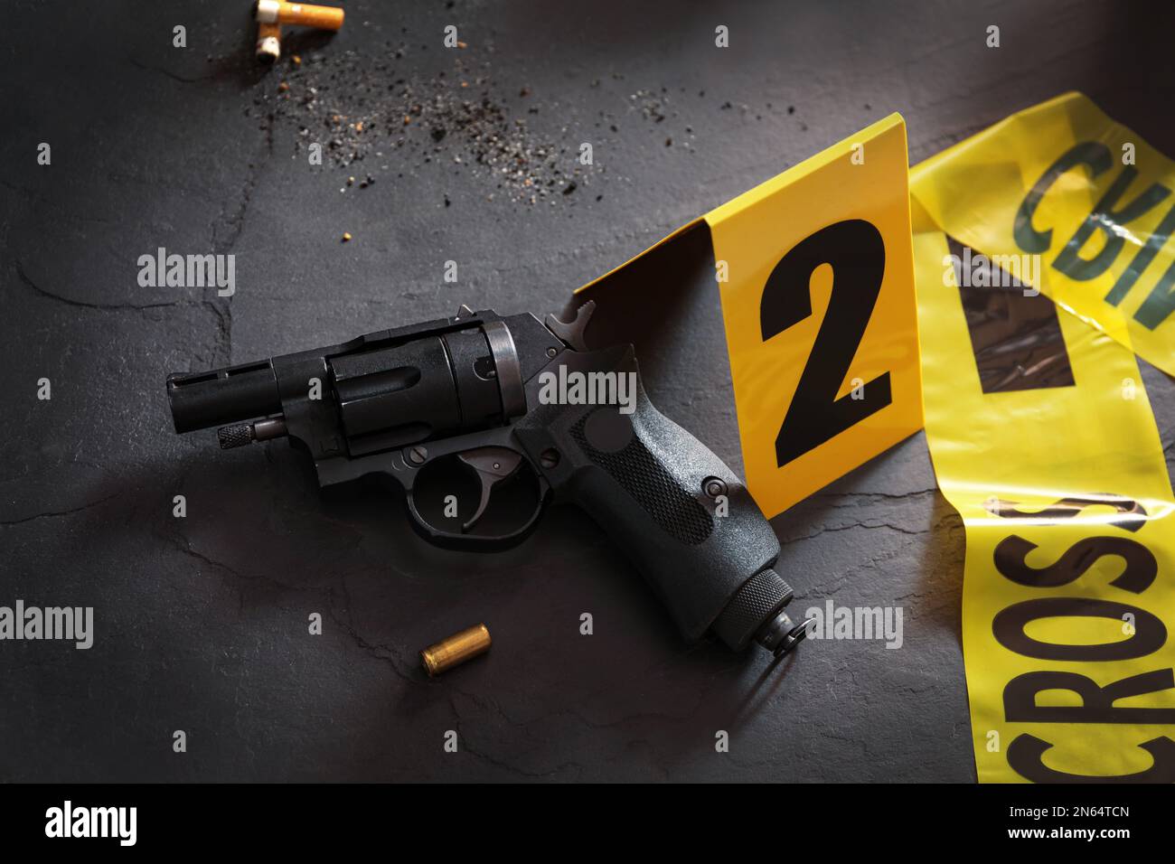 Composition with gun and shell casing on black slate table. Crime scene ...