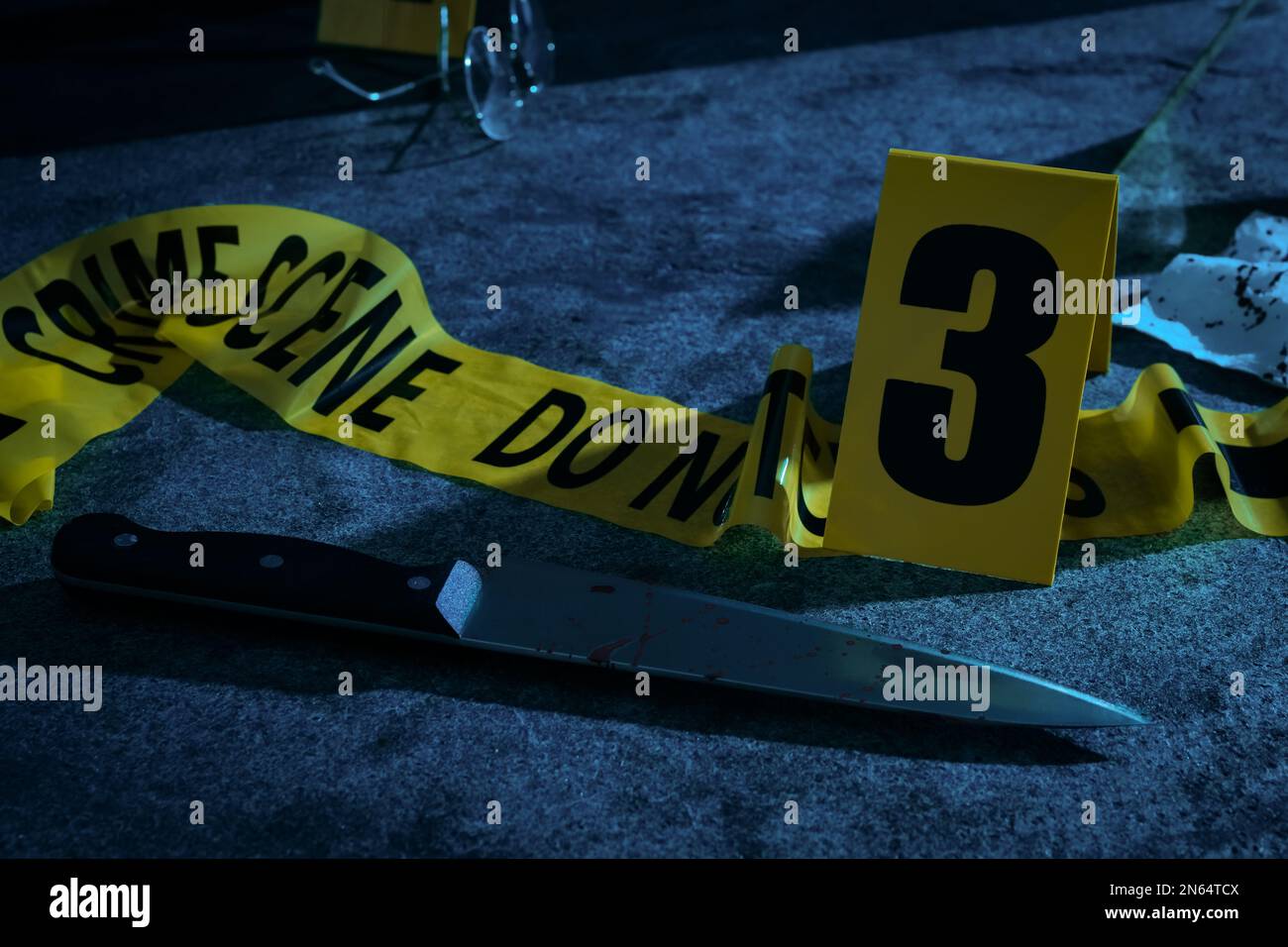 Yellow tape, crime scene marker and bloody knife on grey stone table at ...