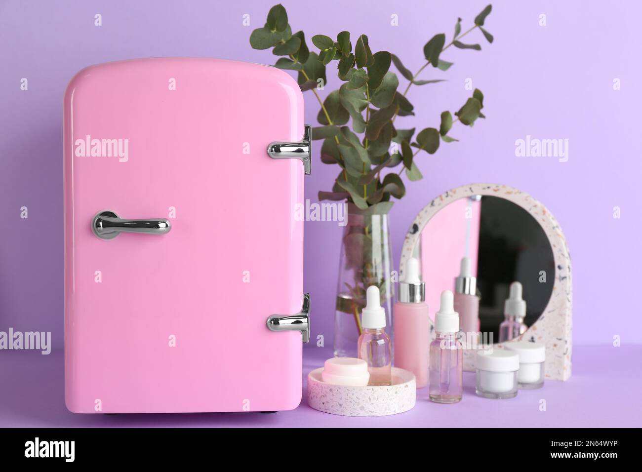 Cosmetic refrigerator and skin care products on violet background Stock ...
