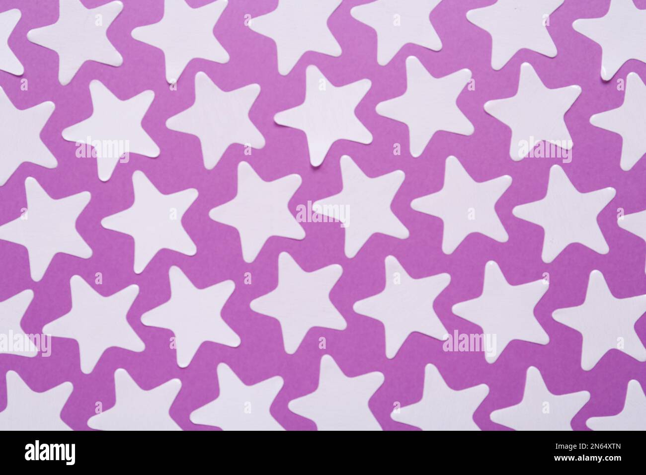 White star shaped confetti on violet background, flat lay Stock Photo ...