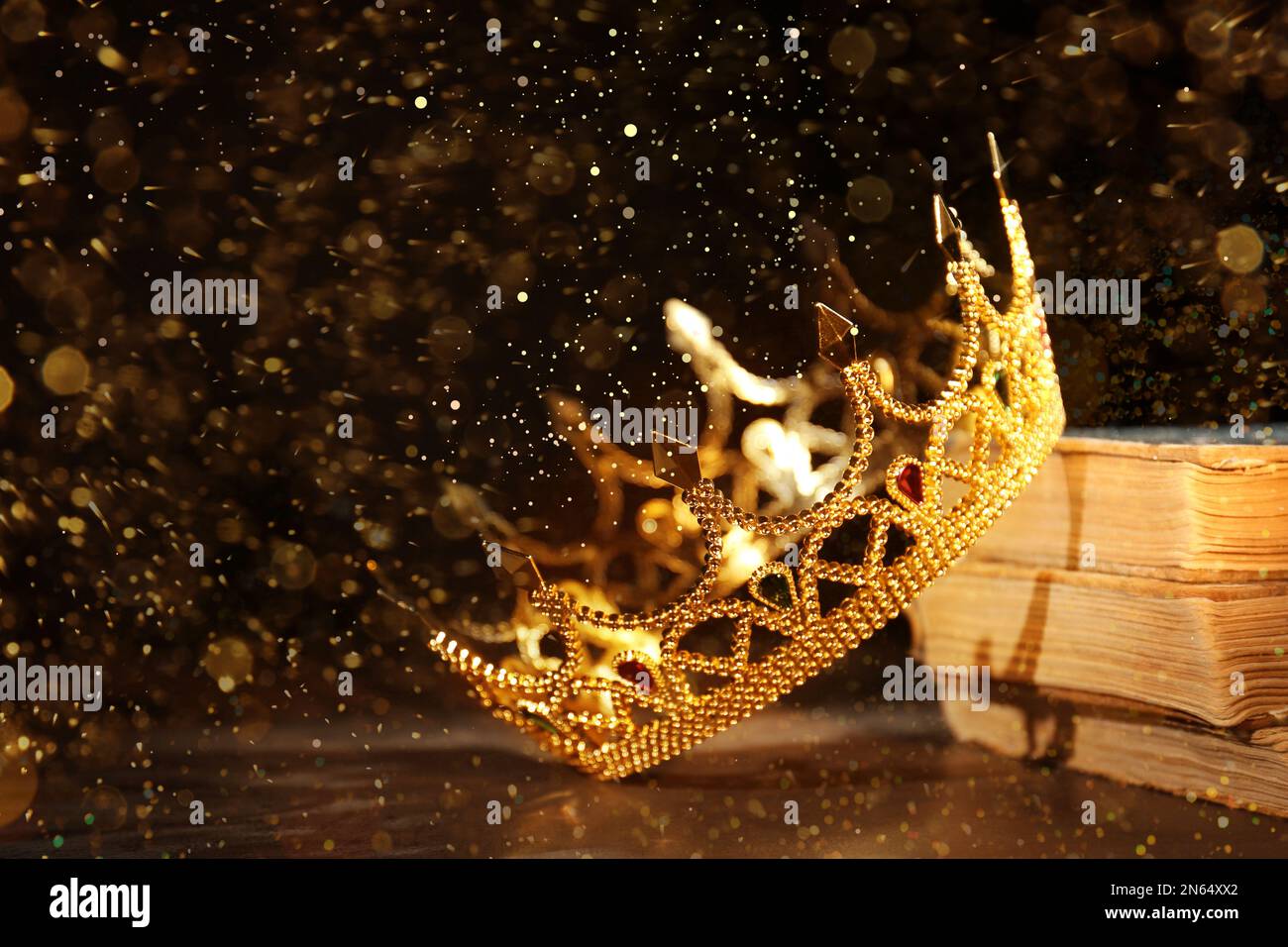 Fantasy world. Beautiful golden crown and old books on table, bokeh ...