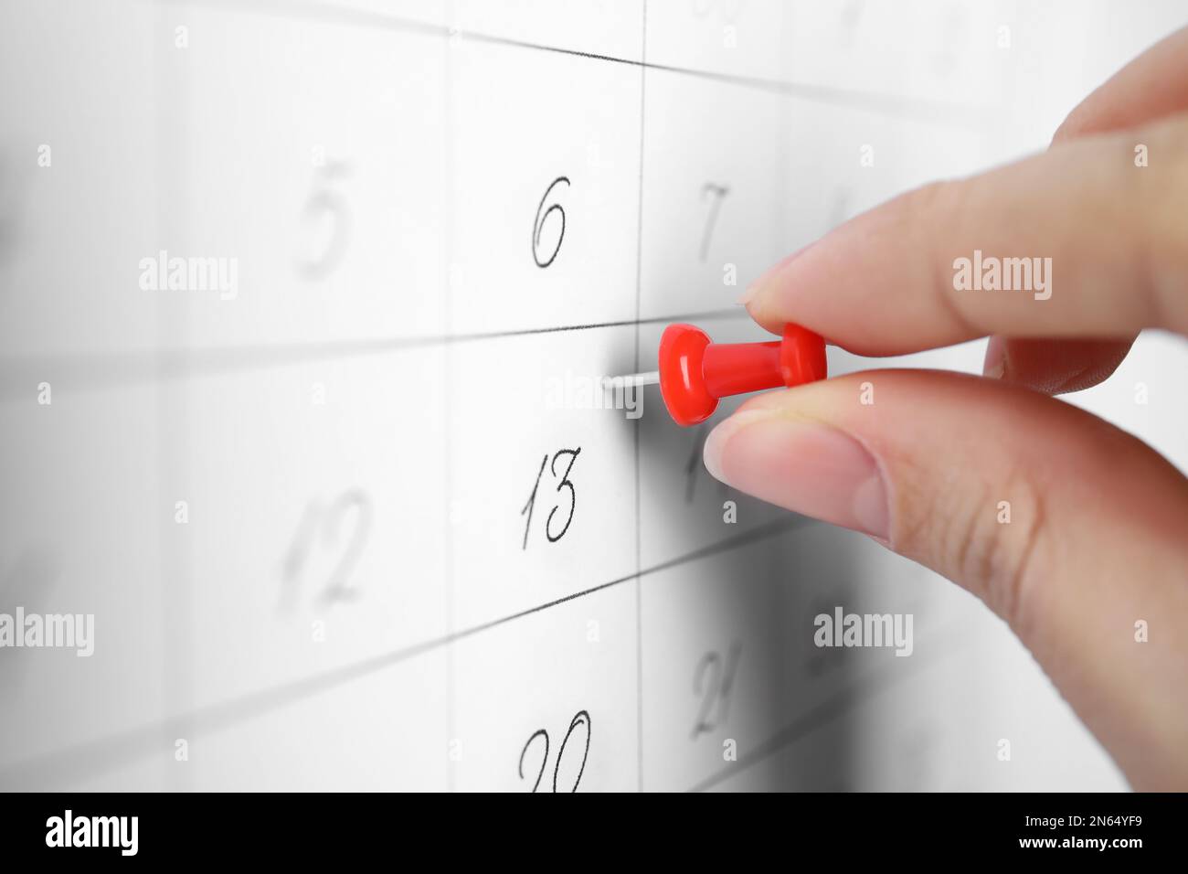 Woman pinning Friday 13th on calendar, closeup. Bad luck superstition ...