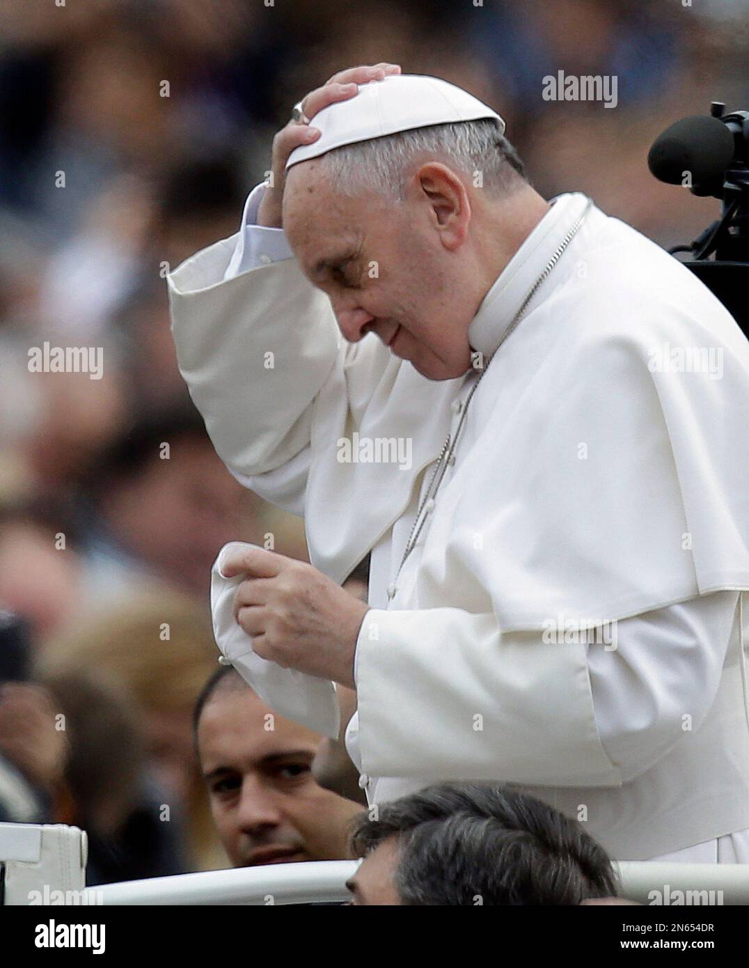 Pope Francis puts on a skull cap given to him a faithful in the crowd ...