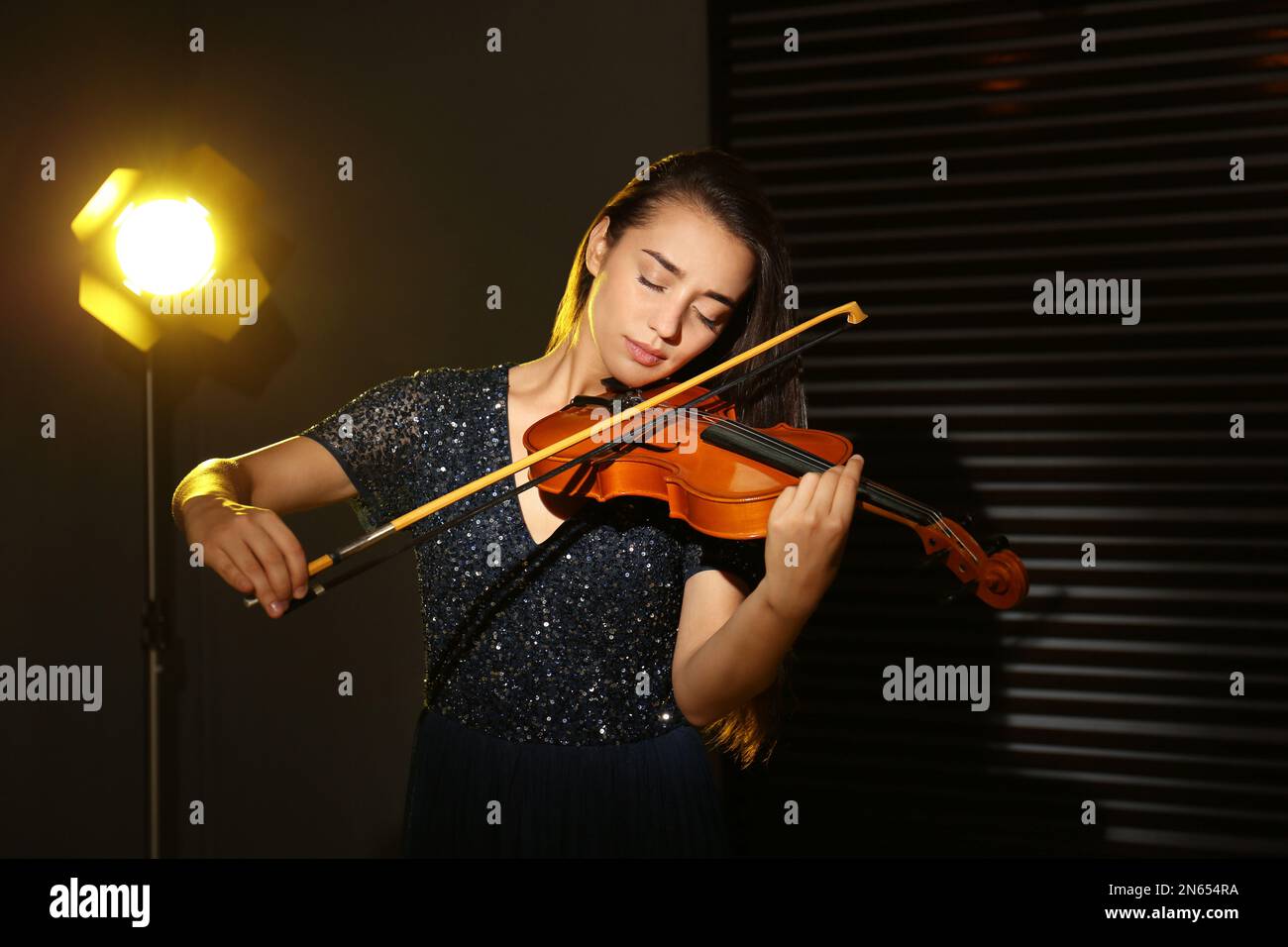 Beautiful young woman playing violin in dark room Stock Photo - Alamy