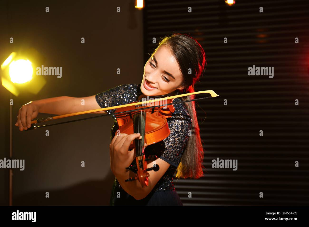 Beautiful young woman playing violin in dark room Stock Photo - Alamy