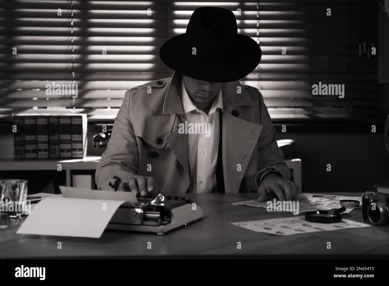 Old fashioned detective at table in office. Black and white effect ...