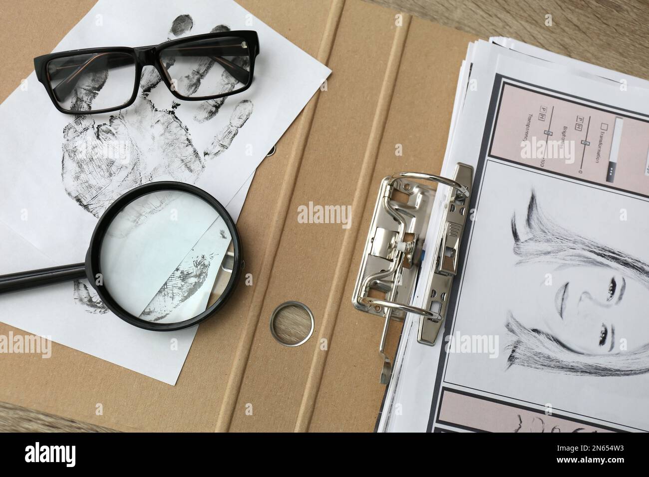 Papers with suspect's portrait, palm print and magnifying glass on ...