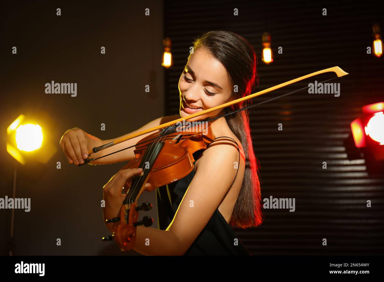 Beautiful young woman playing violin in dark room Stock Photo - Alamy