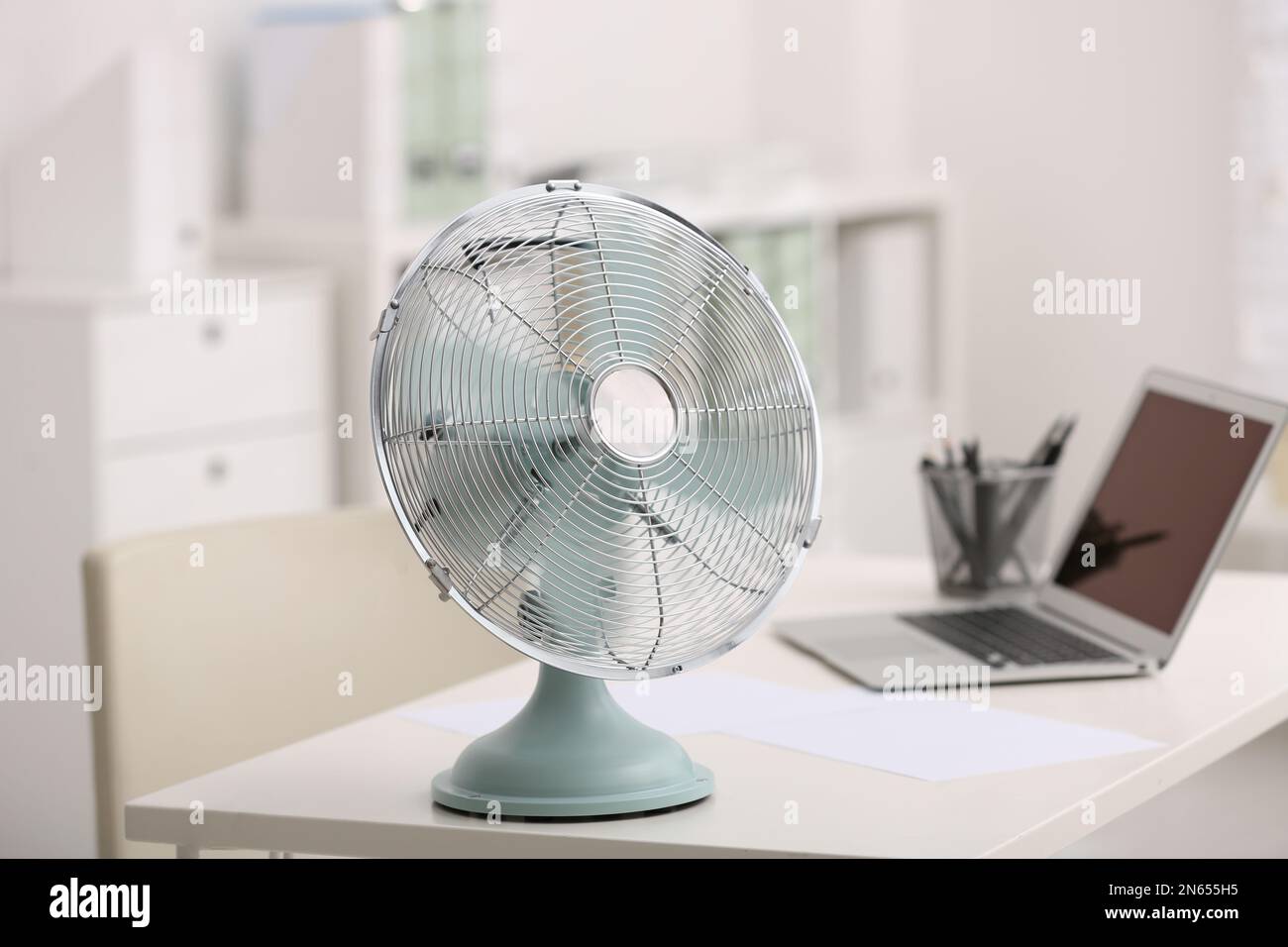 Modern electric fan on table in office Stock Photo - Alamy