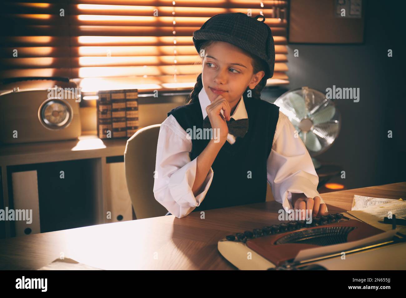 Cute little detective using typewriter at table in office Stock Photo ...